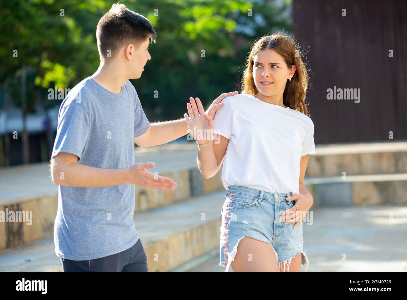 Girl gesturing stop to man flirting with her Stock Photo - Alamy