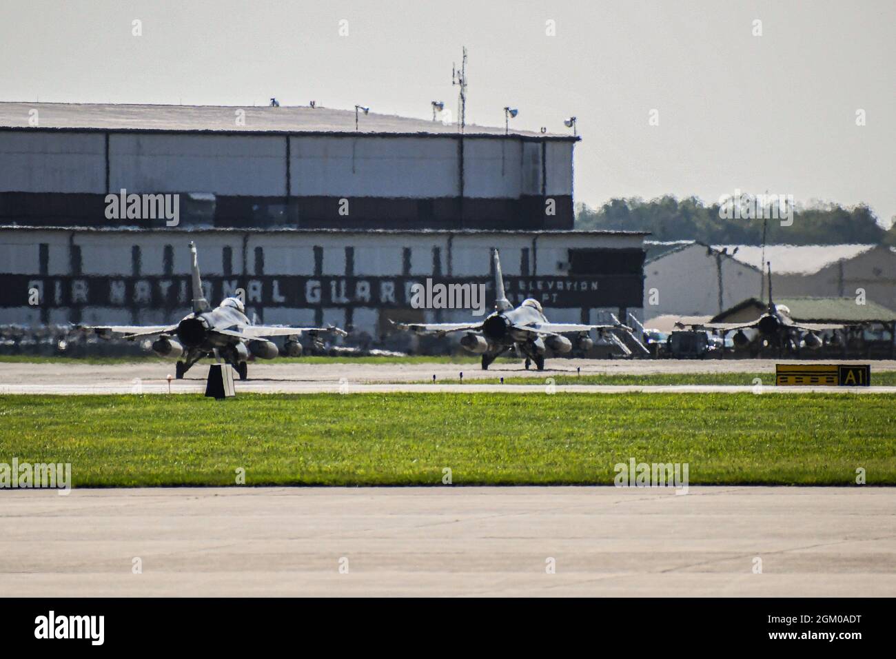 Hangar 1 is seen behind three F-16 Fighting Falcon aircraft as they ...