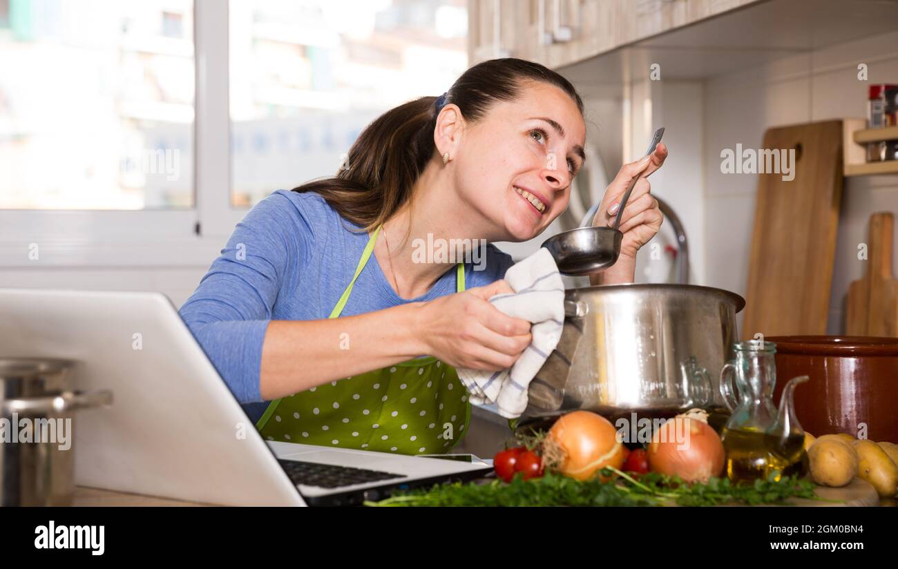 Housewife cooking with help of laptop Stock Photo - Alamy