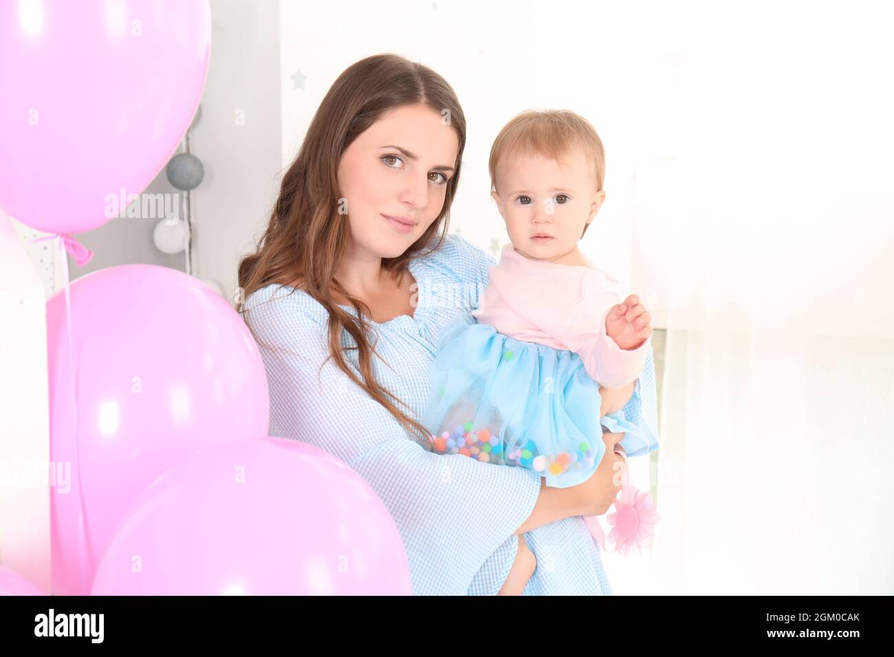 Young mother holding cute baby on birthday party at home Stock Photo - Alamy