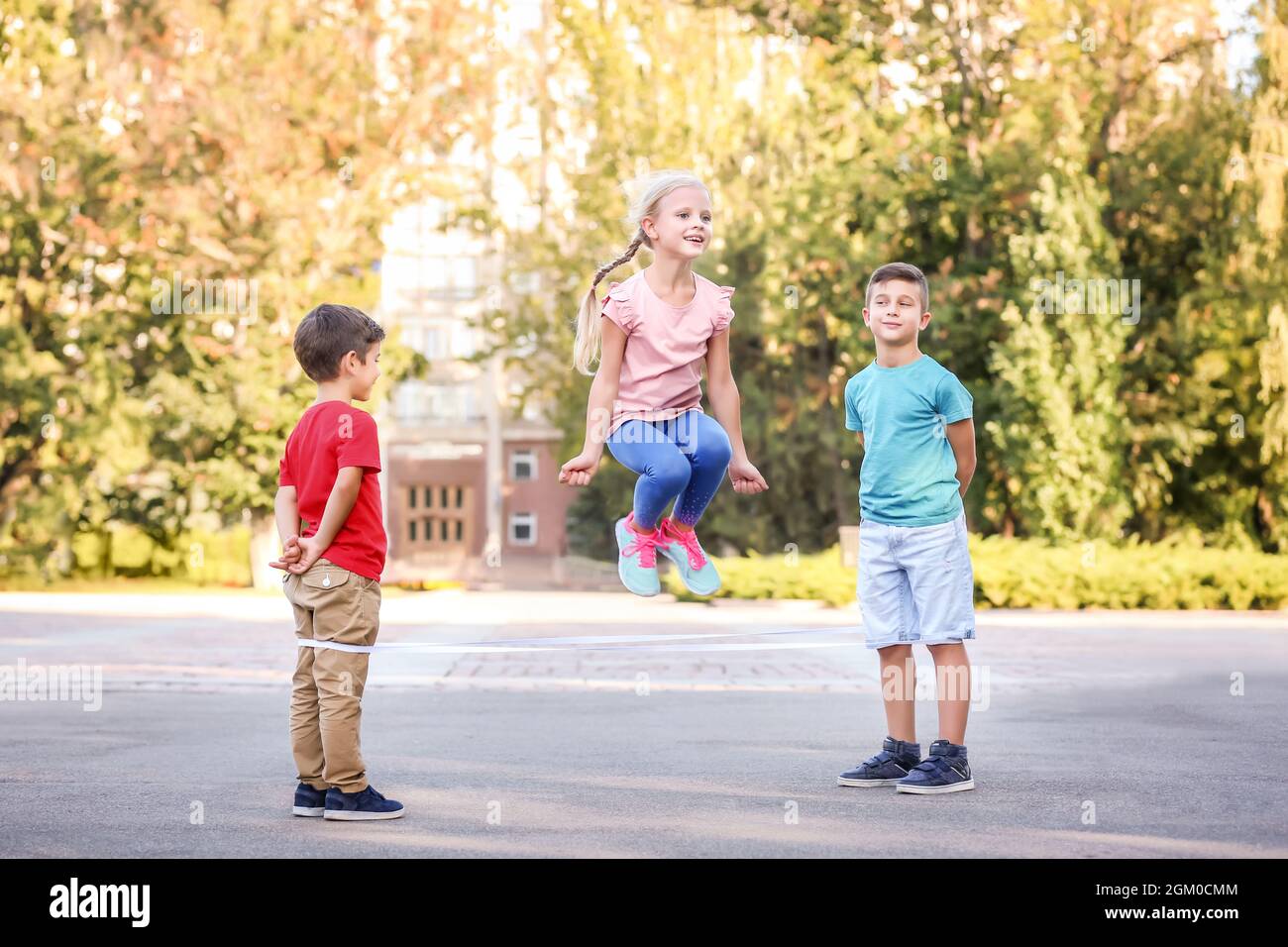 Adorable children playing elastic game outdoors Stock Photo - Alamy