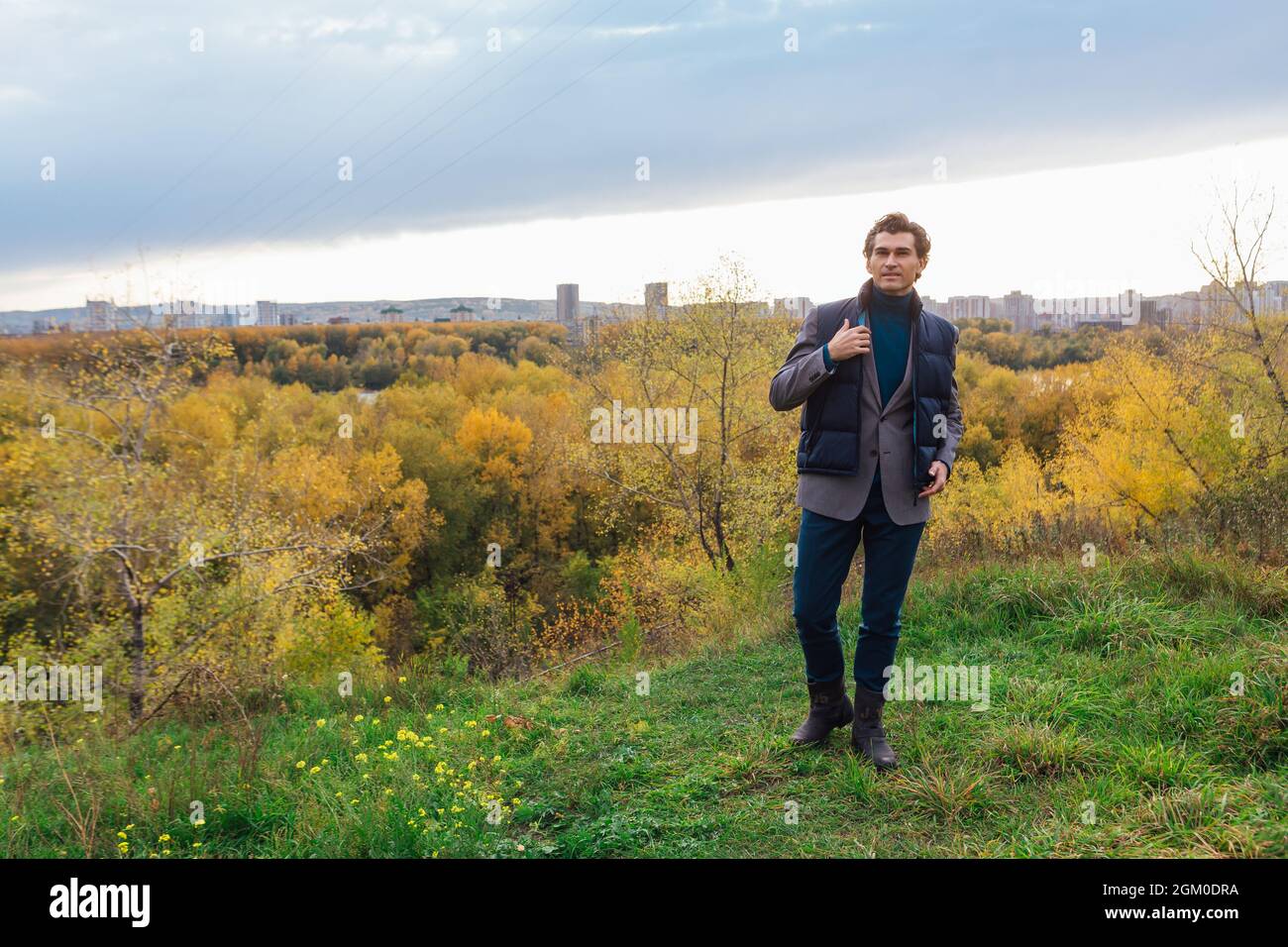 Tall handsome man walking outdoor in yellow autumn forest on the hill ...