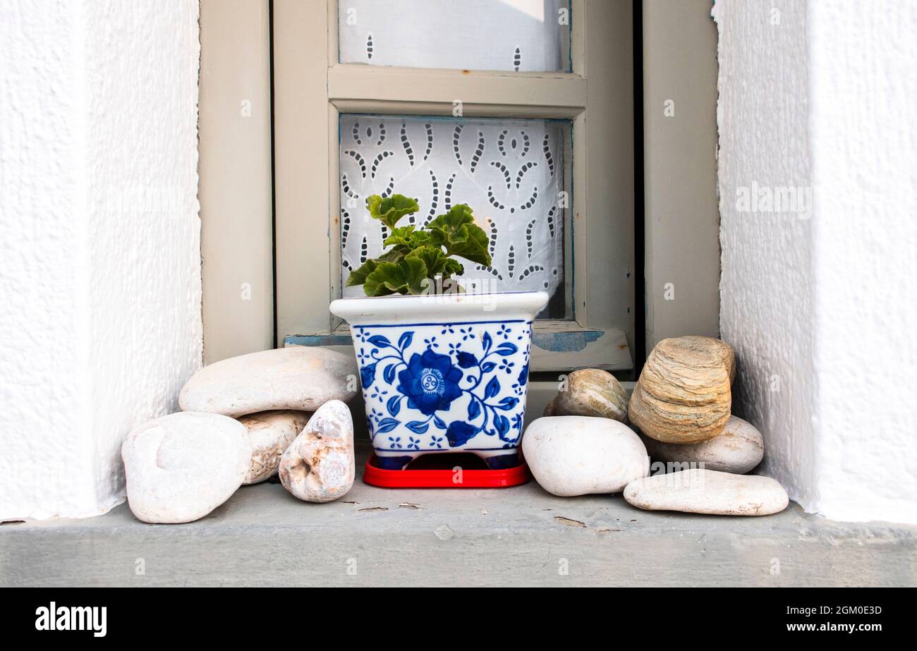 simple window decoration of round white rocks, blue and white pot and ...