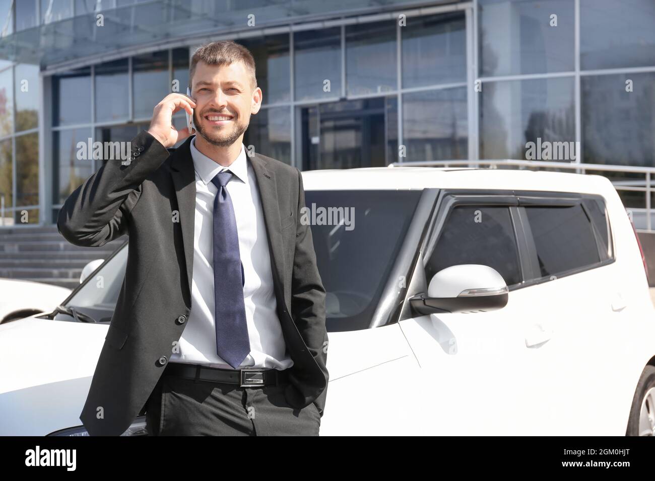 Salesman talking on phone near new car outdoors Stock Photo - Alamy