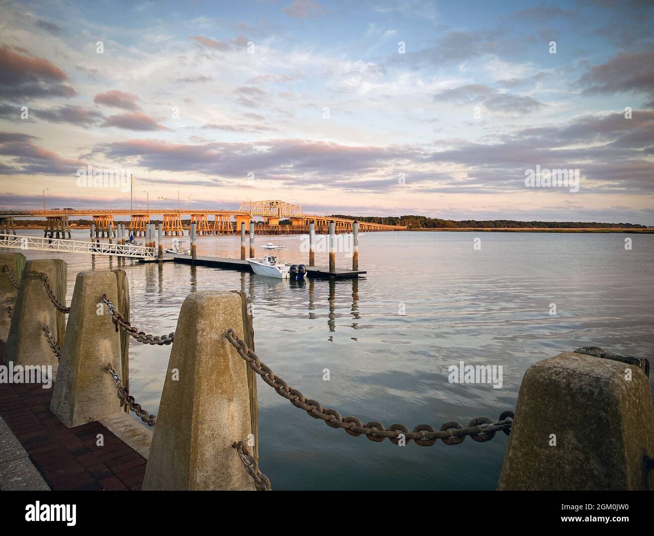 Dockside view with concrete pylons and wooden dock with bridge in ...