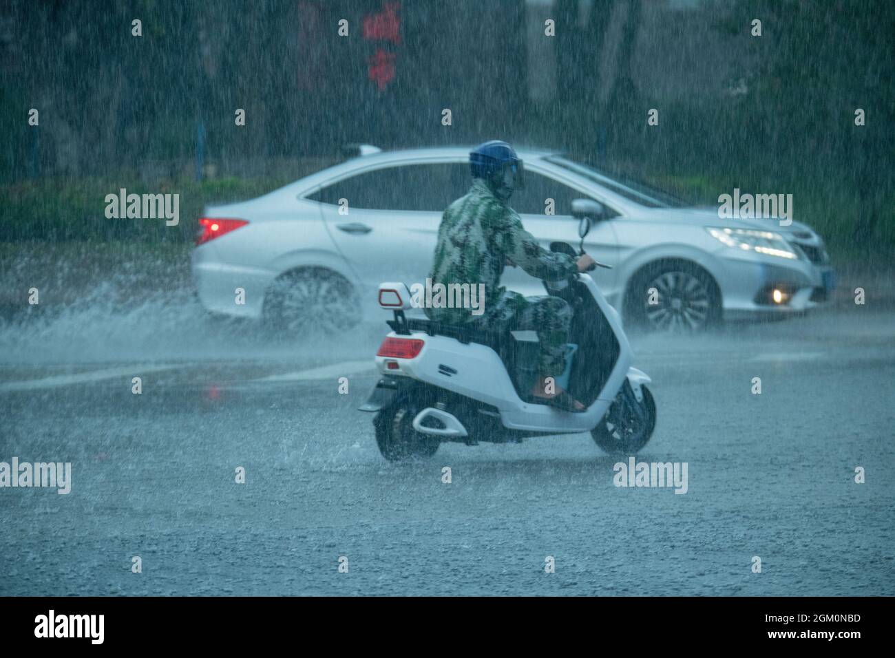 People ride in the rainstorm brought by Typhoon Conson, the 13th ...