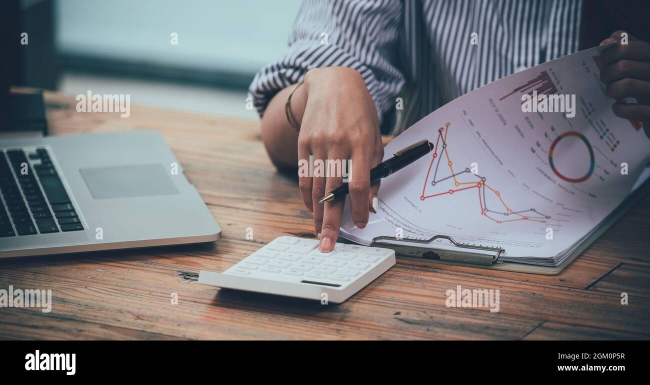 Close up business woman working on desk office with using a calculator ...