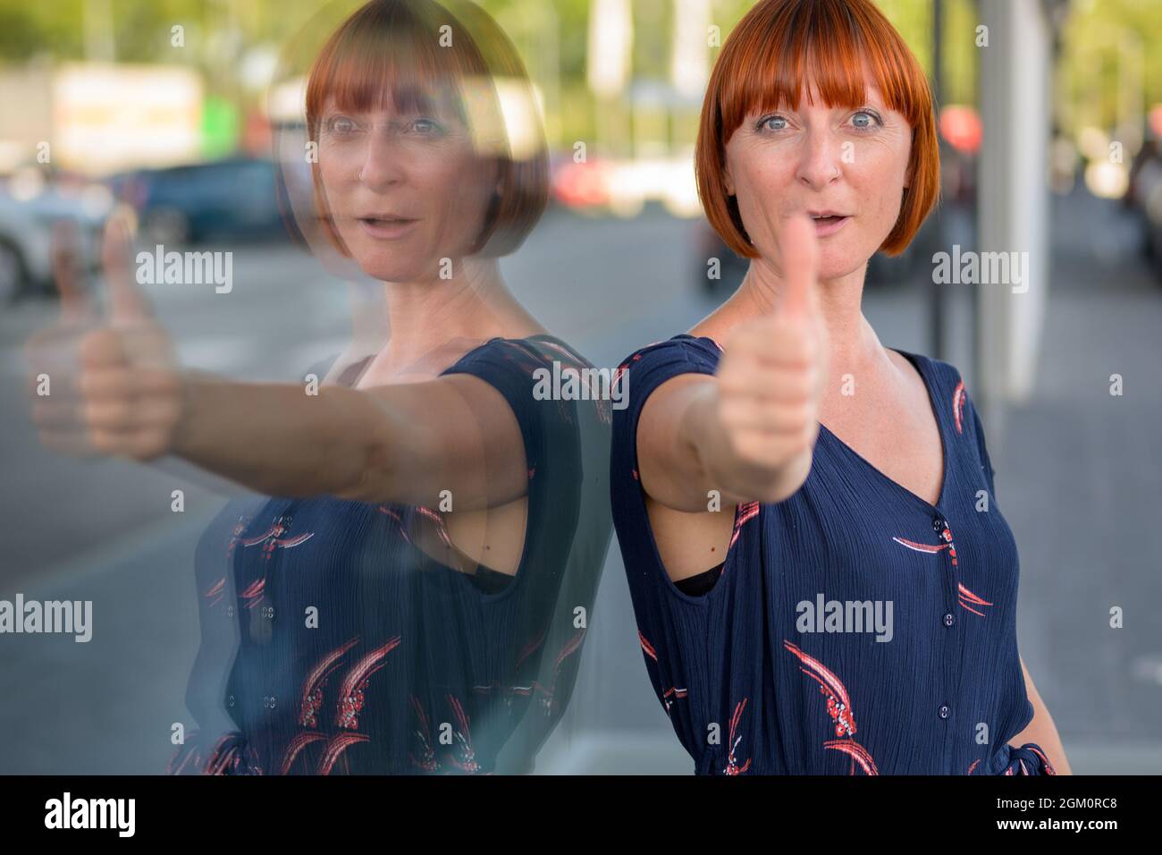 Attractive enthusiastic redhead woman giving a thumbs up gesture with a ...