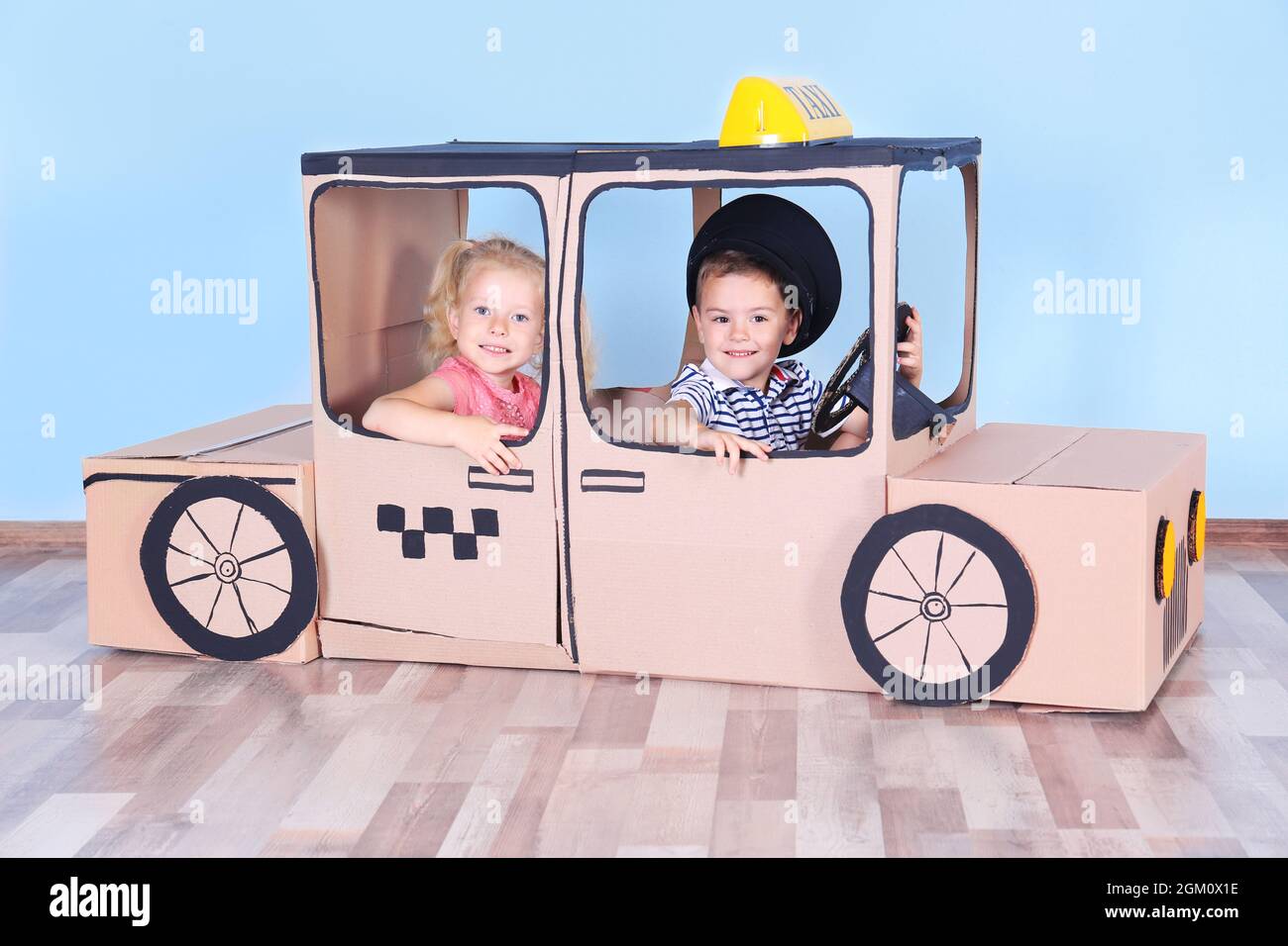 Little children playing with cardboard taxi in light room Stock Photo ...