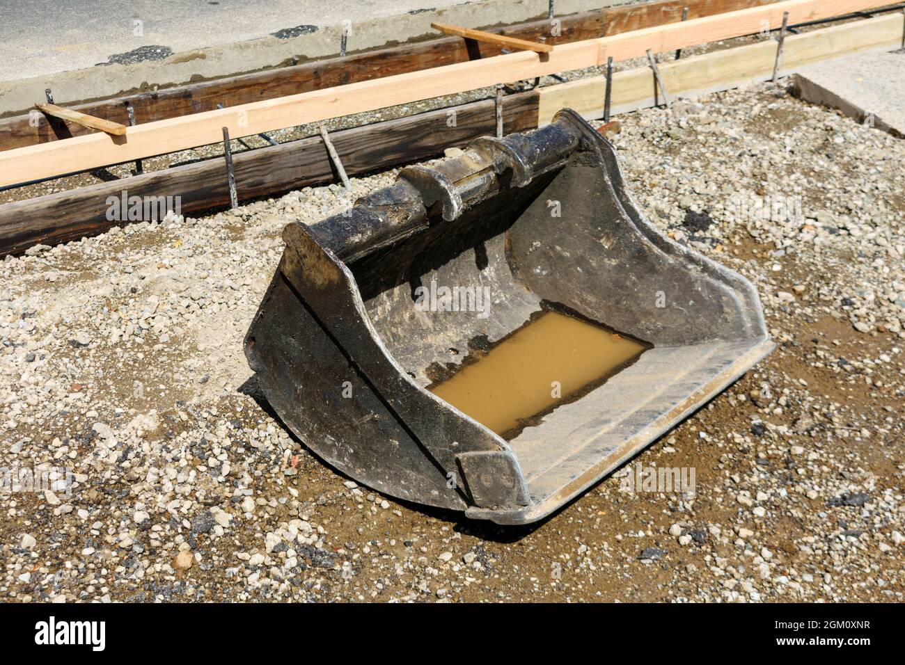 Detached excavator bucket partially filled with dirty water on ...