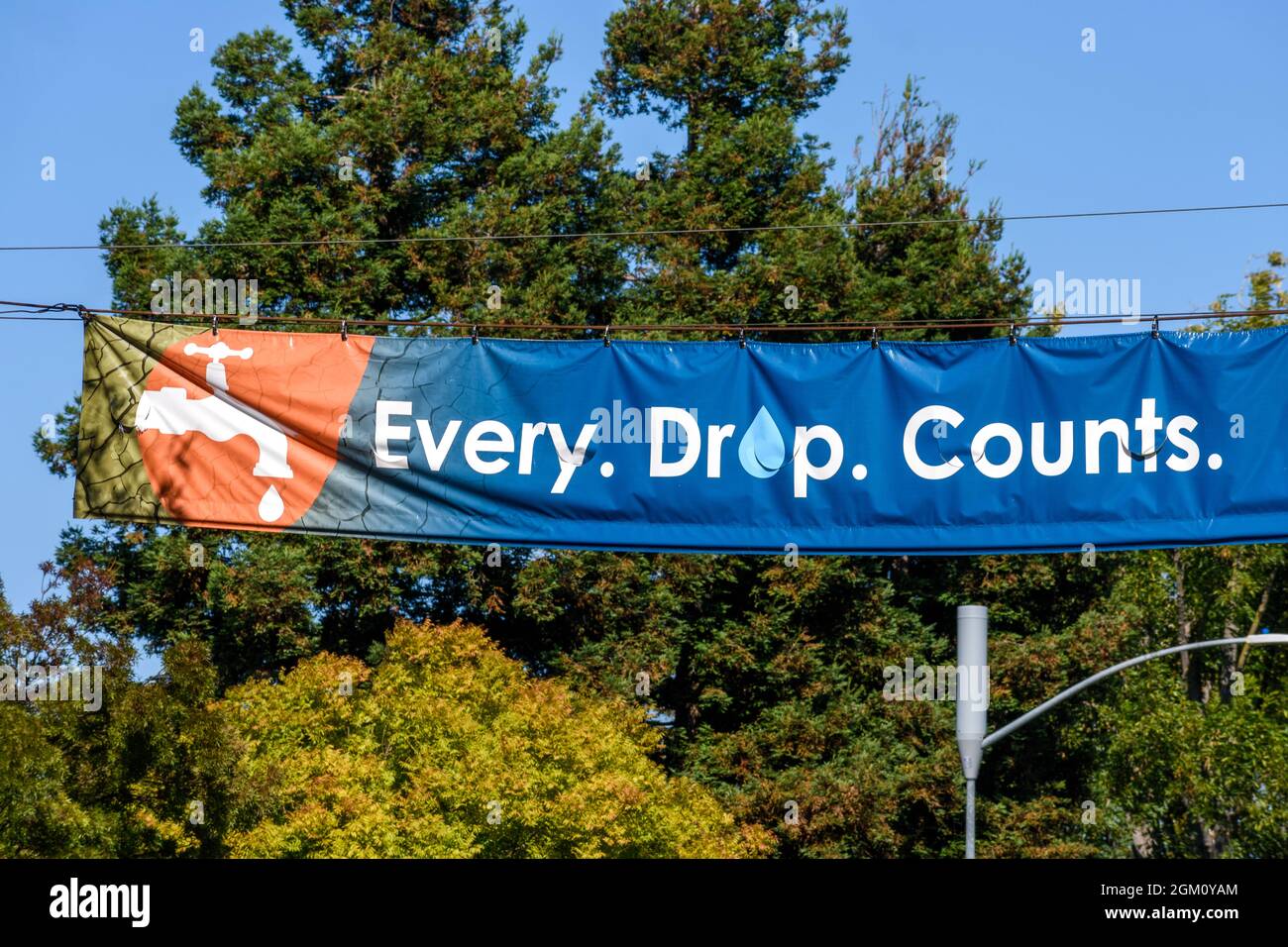 Every Drops Counts banner over the street. Green trees, blue sky ...