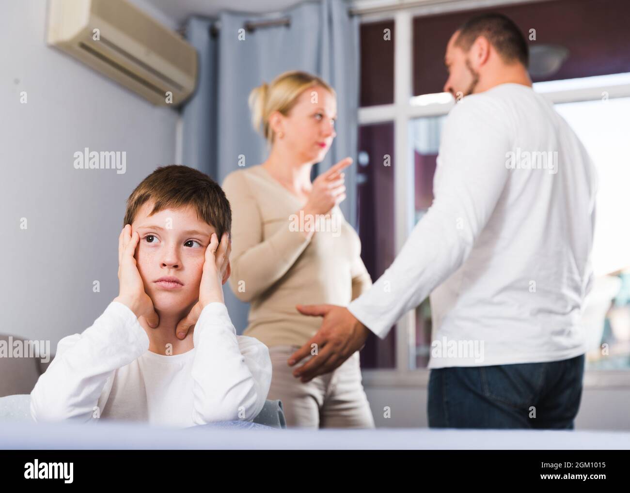 Upset son suffering from parents arguing Stock Photo - Alamy