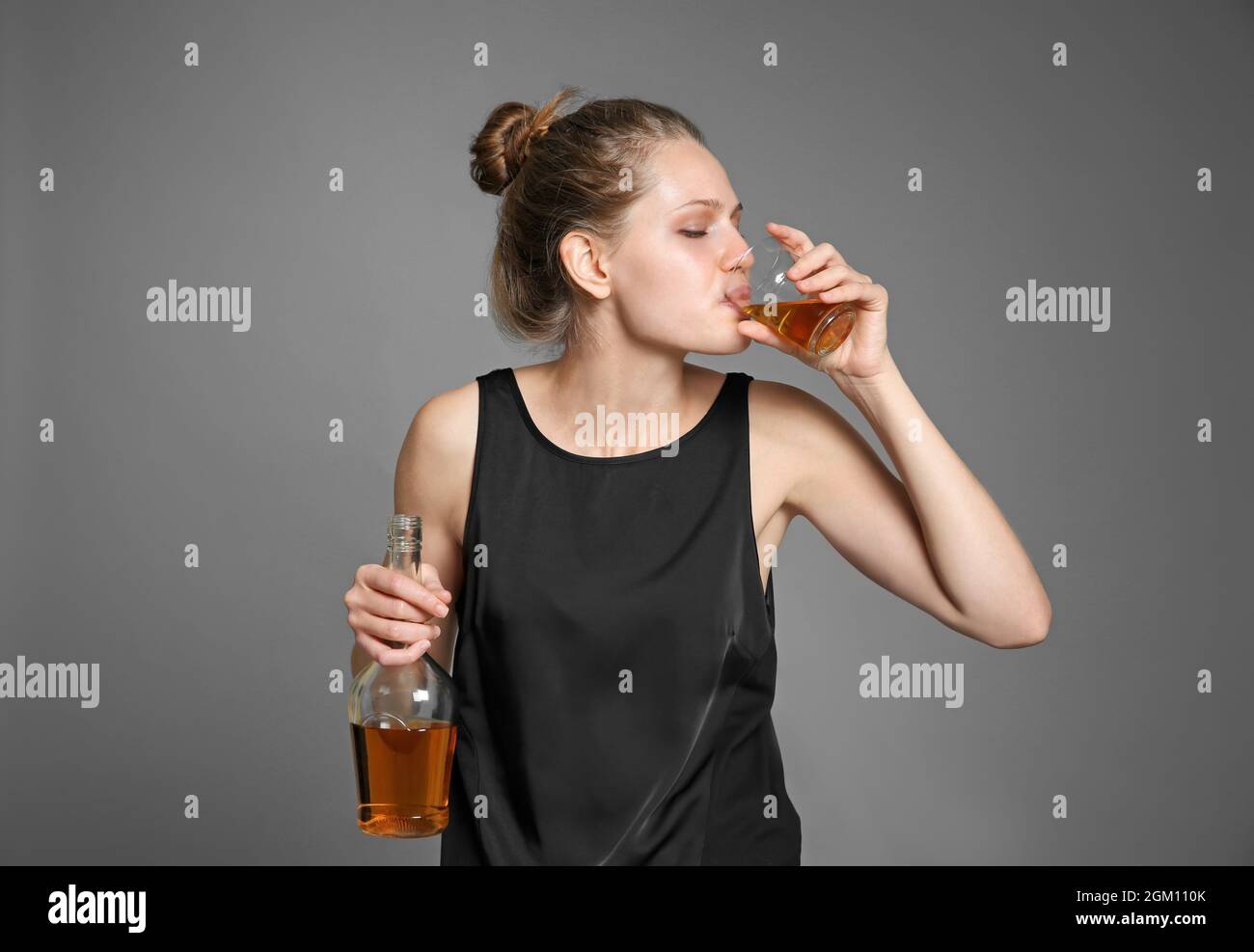 Young woman drinking alcohol on color background Stock Photo - Alamy