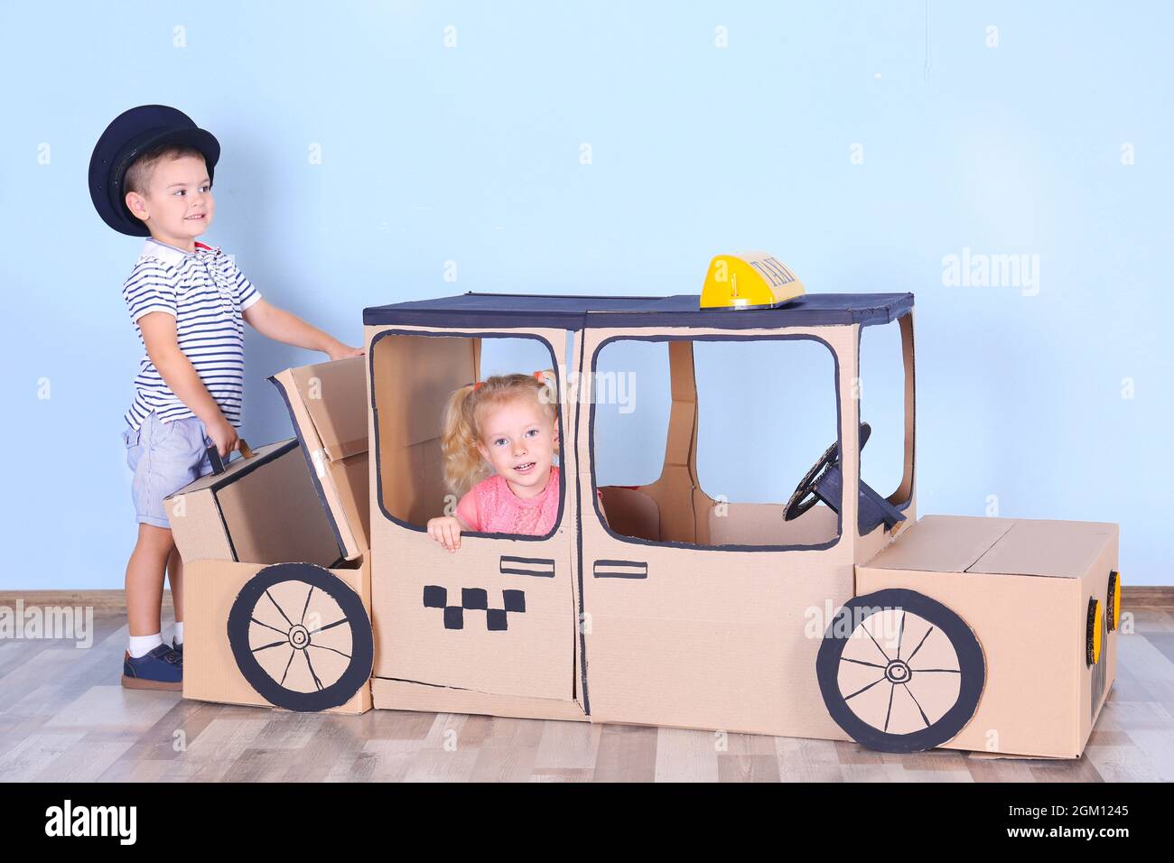 Little children playing with cardboard taxi in light room Stock Photo ...
