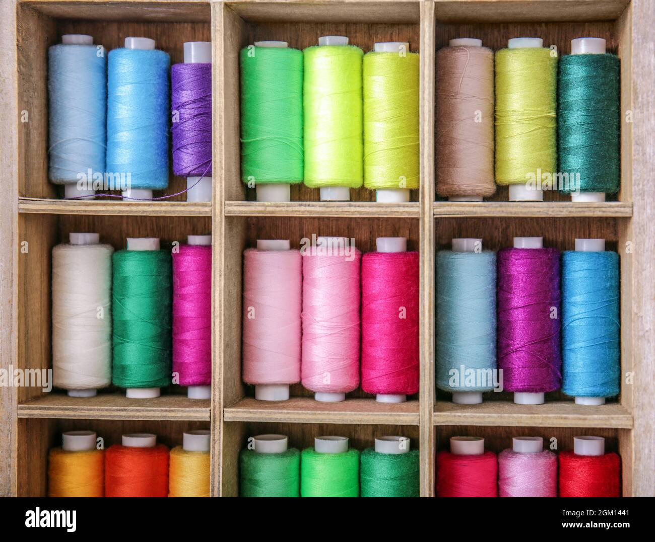 Wooden stand with different colorful threads Stock Photo - Alamy