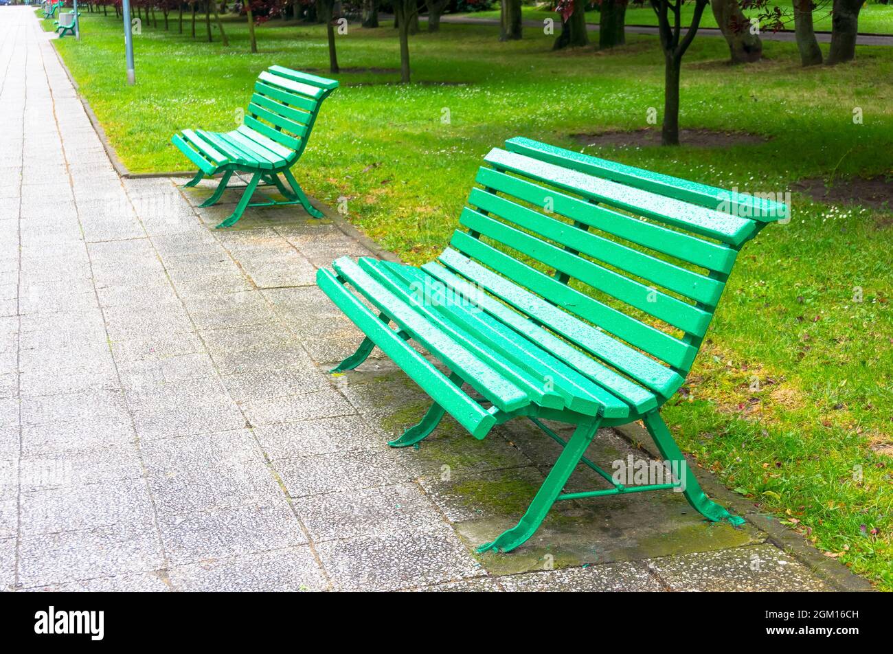 Wooden green benches by the sidewalk in a city park Stock Photo - Alamy