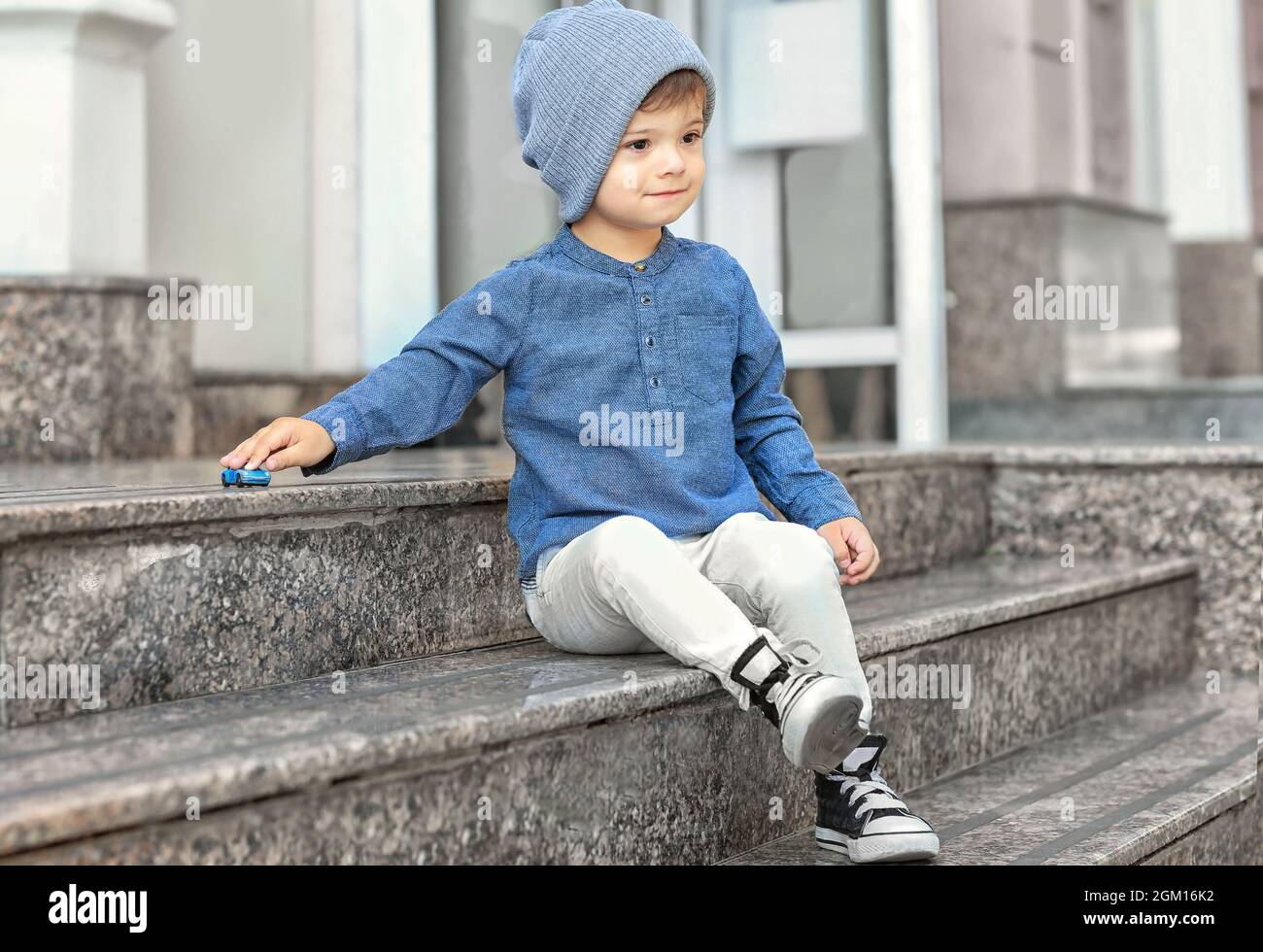 Adorable little boy sitting on stairs outdoors Stock Photo - Alamy