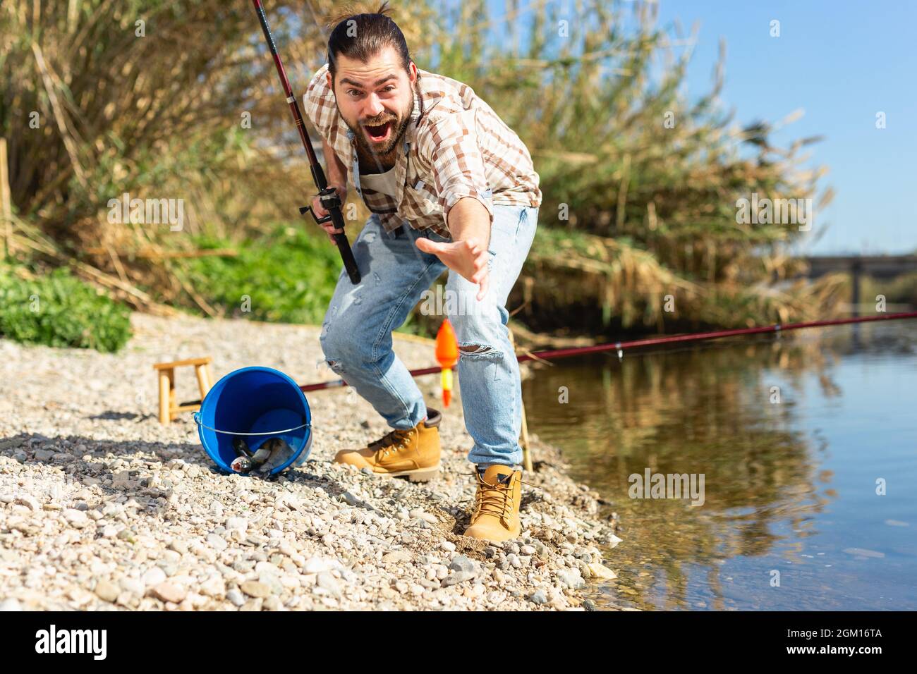 Happy fisherman pulls fish out of the river Stock Photo - Alamy