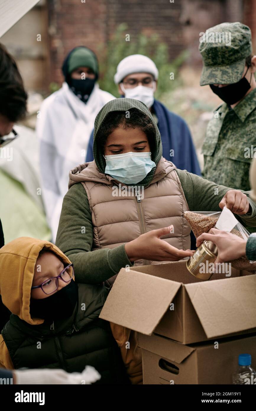PHand of social worker putting products into cardboard box to refugee ...