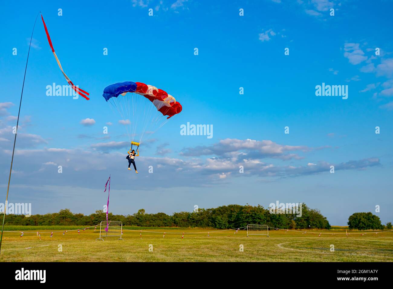 Parachutist with an open parachute is flying and slows down for landing ...
