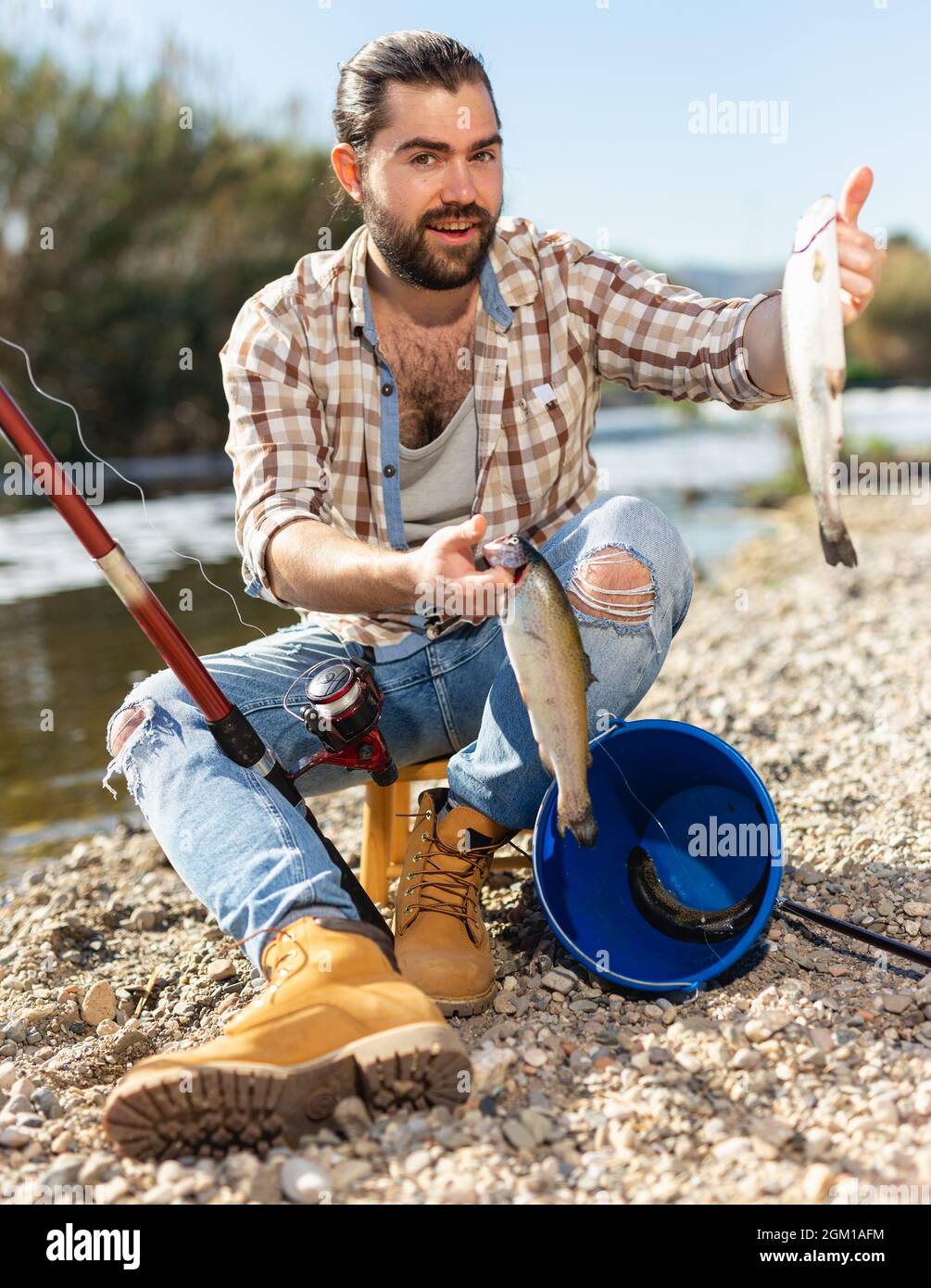 Positive fisherman holding catch freshwater fish in hands Stock Photo ...