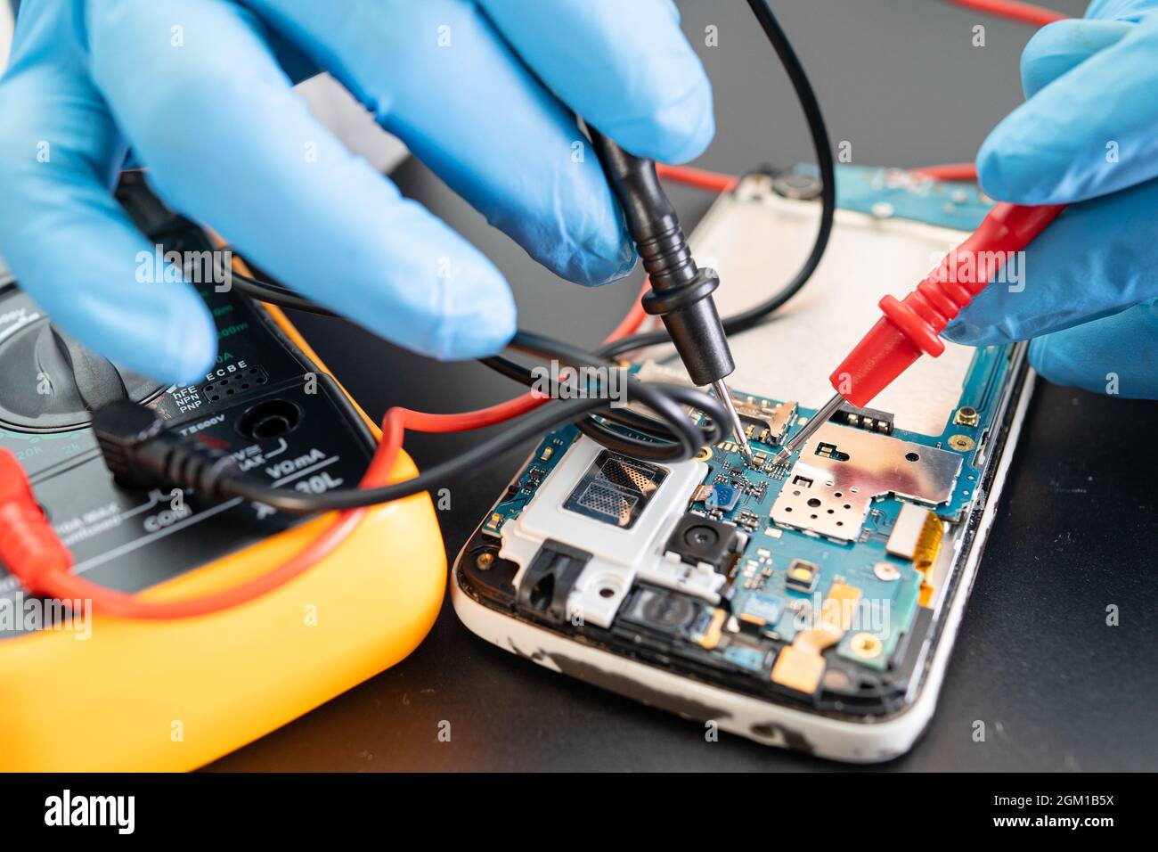 Technician repairing inside of mobile phone by soldering iron ...