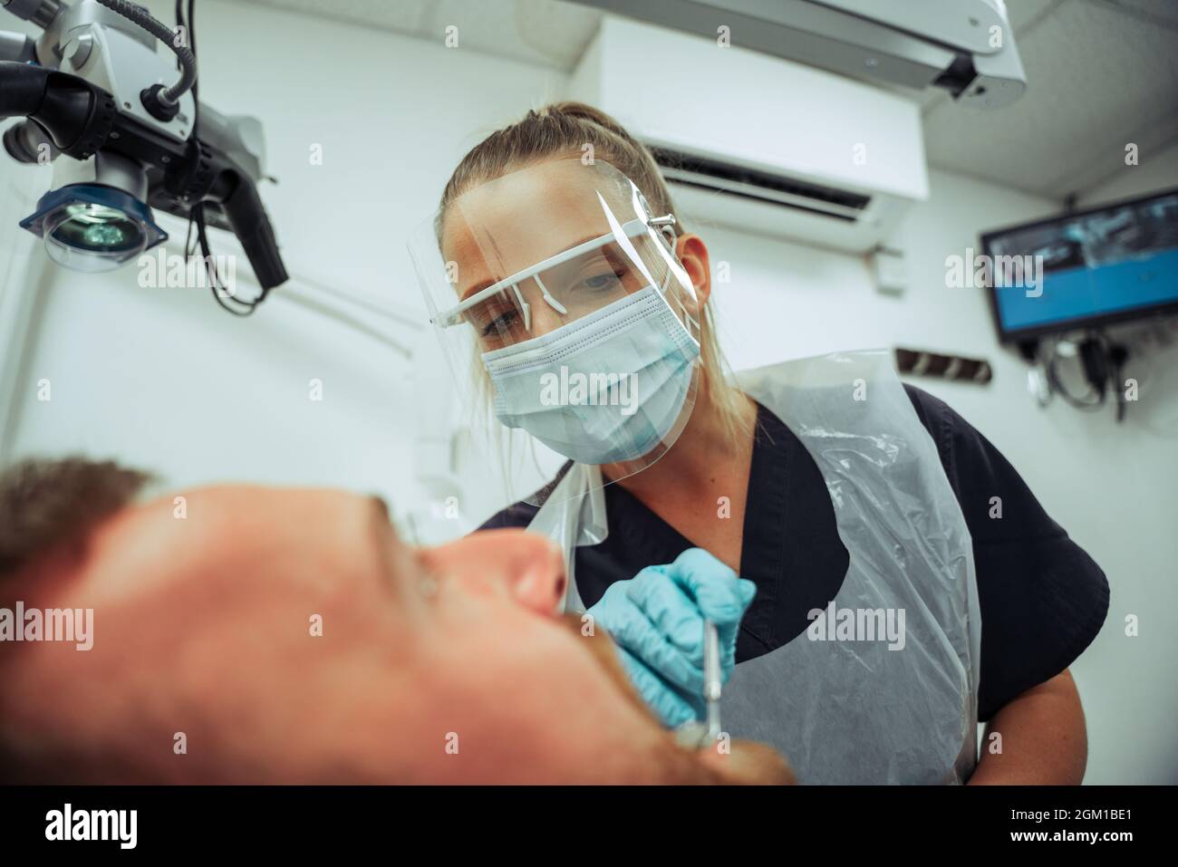 Caucasian male client sitting dentist chair while female nurse operates ...