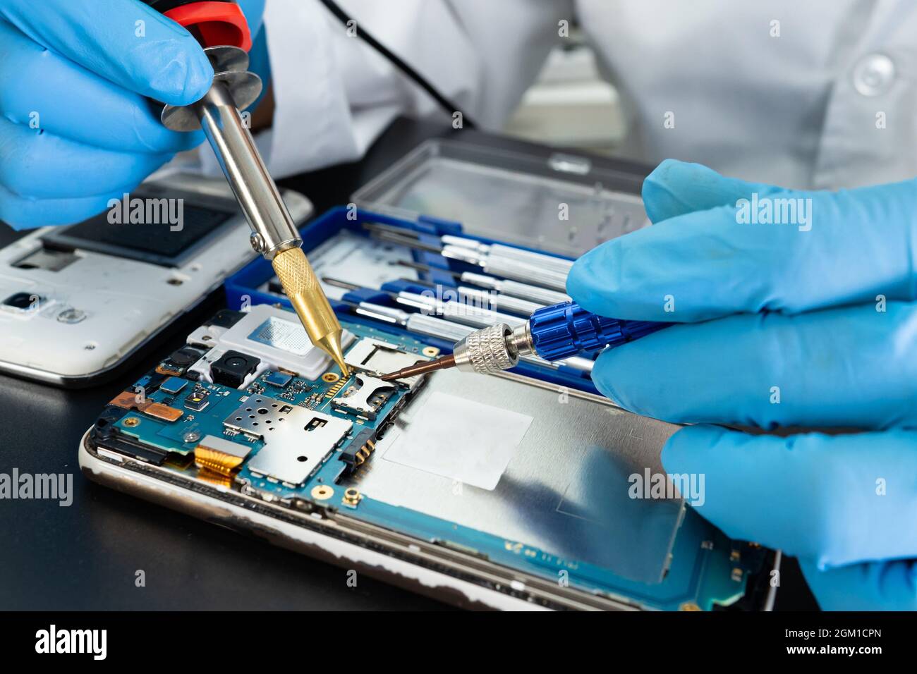 Technician repairing inside of mobile phone by soldering iron ...