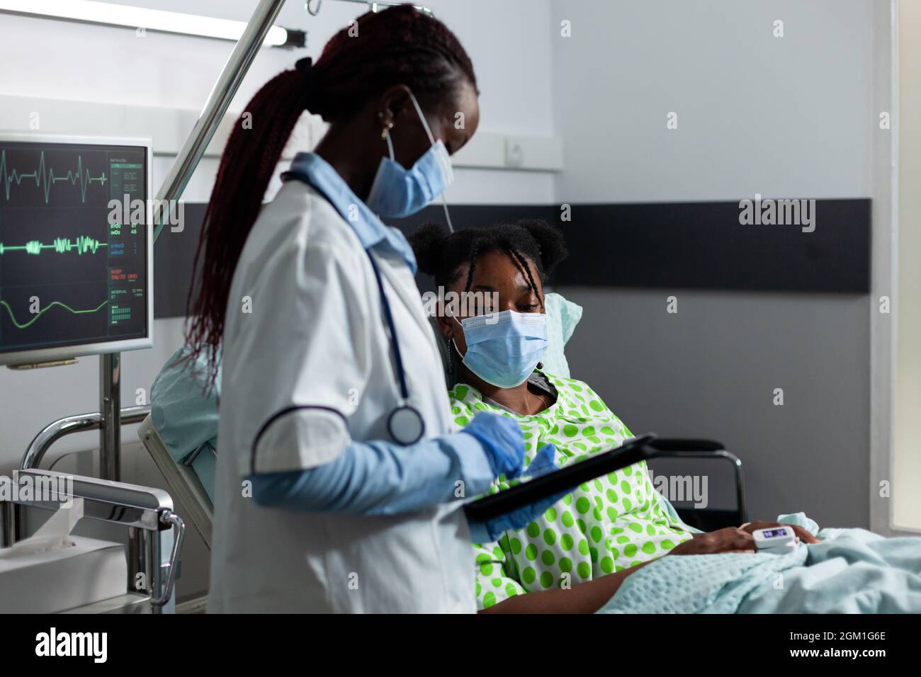 Medic of african ethnicity helping sick patient at clinic in hospital ...