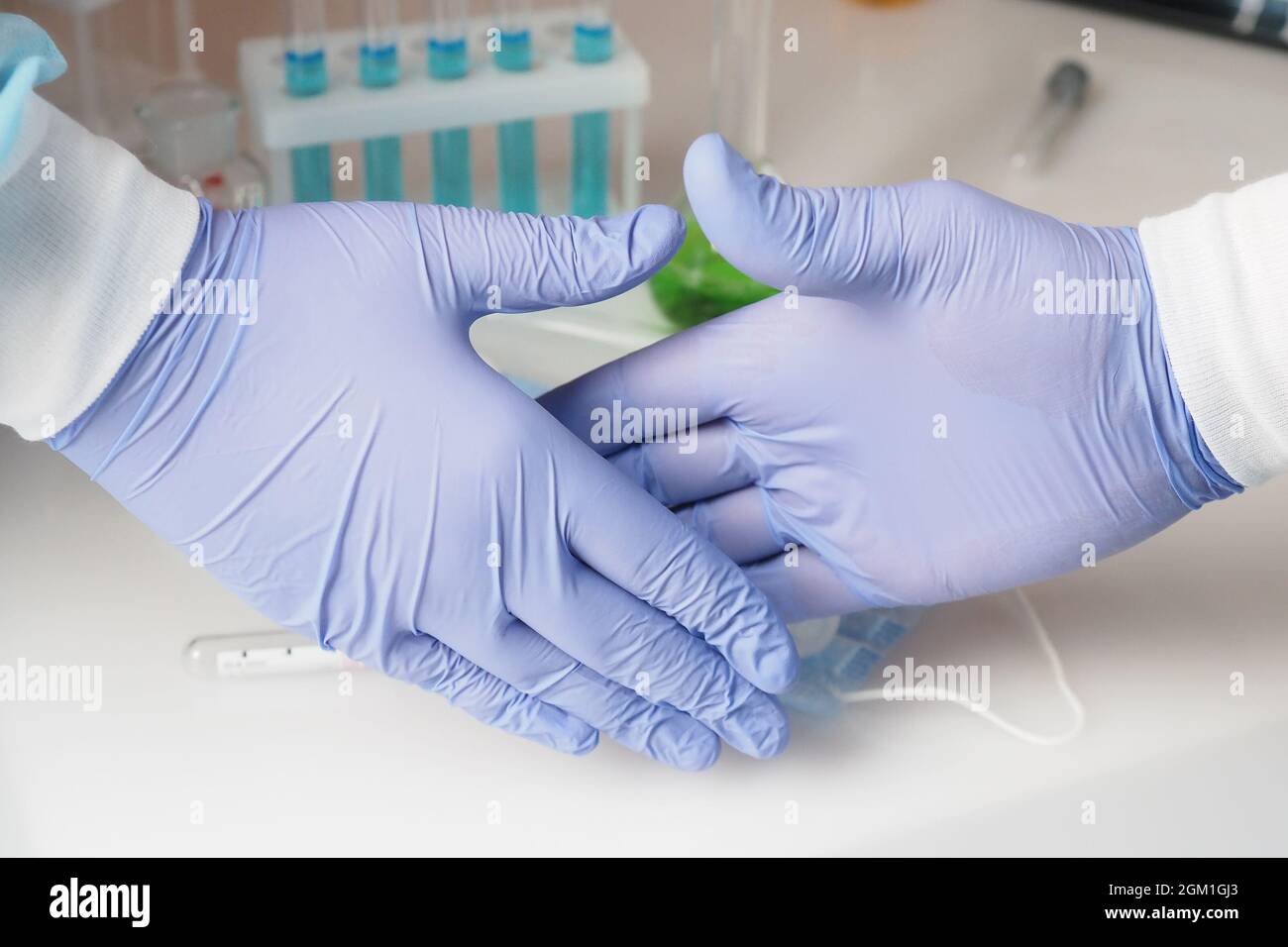 Two hands wearing medical gloves in a handshake Stock Photo - Alamy