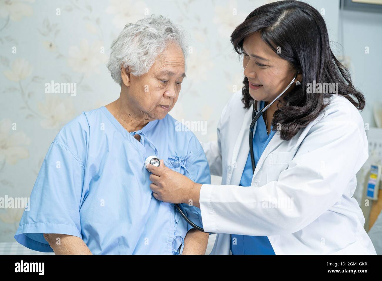 Doctor using stethoscope to checking the patient sit down on a bed in ...
