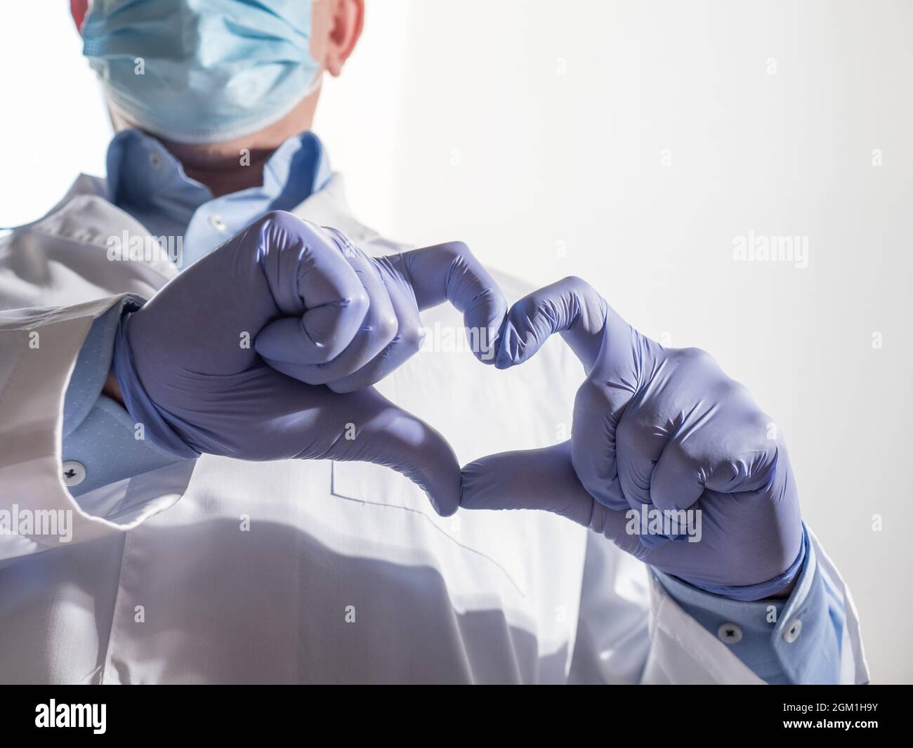 Doctor wearing mask and gloves shows a heart sign Stock Photo - Alamy