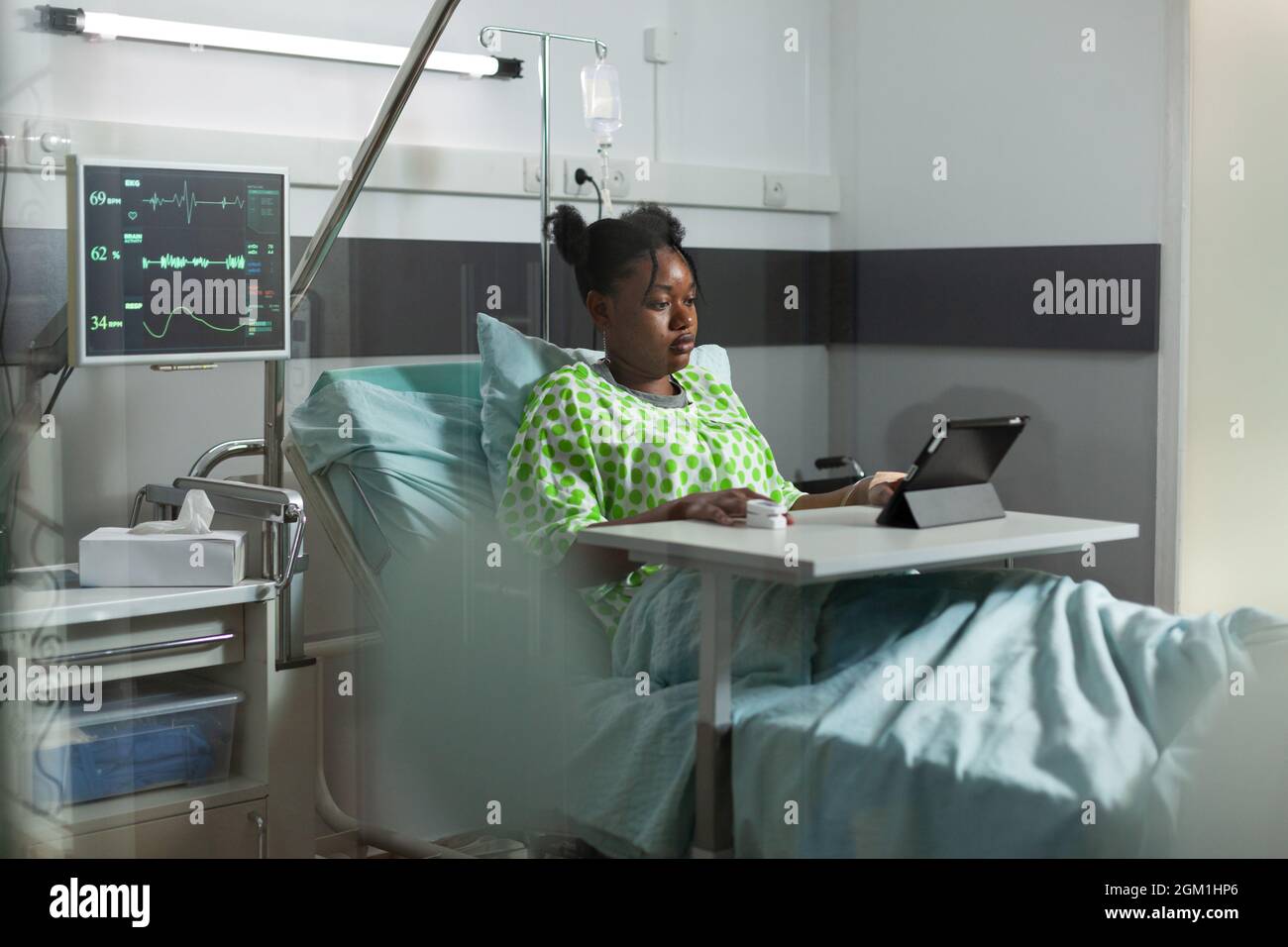 Young african american woman using tablet in hospital ward bed. Sick ...