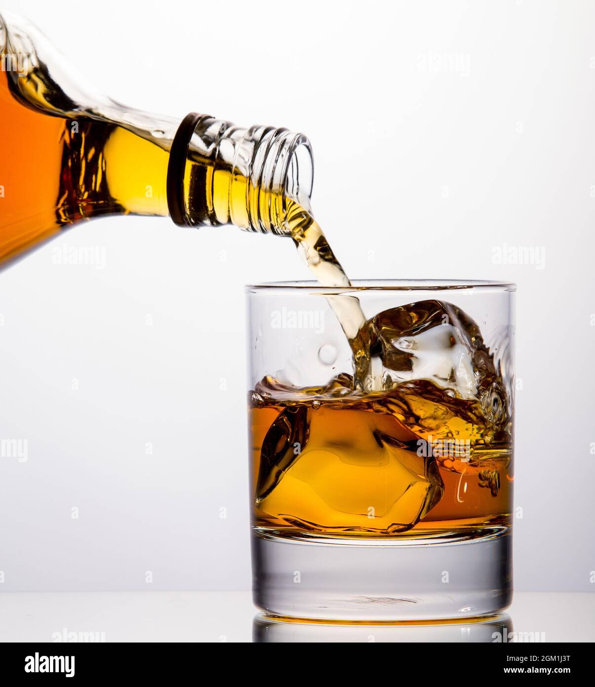 Pouring whisky from a bottle into a tumbler on white background Stock ...
