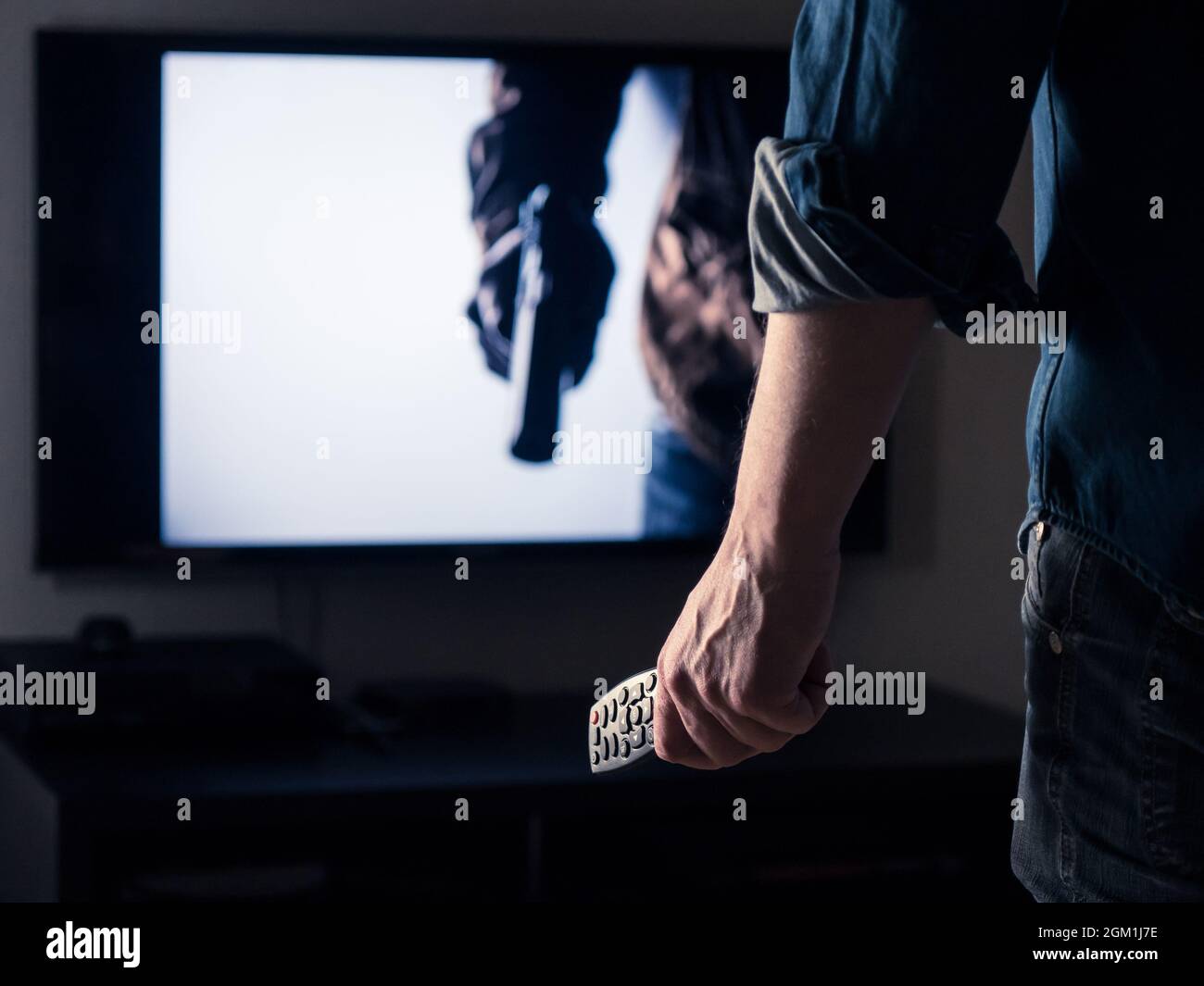 Man holding a tv remote control while watching an action movie. The tv ...
