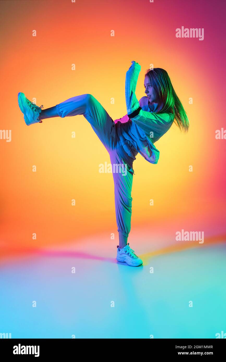 Sportive flexible girl dancing hip-hop in stylish clothes on colorful ...