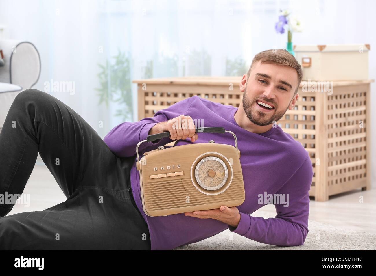 Young man lying and listening to radio in room Stock Photo - Alamy
