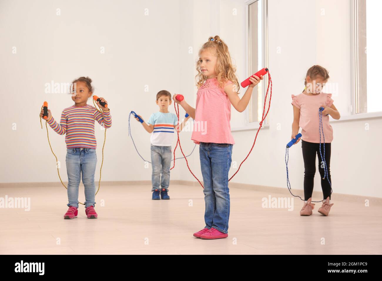 Cute children skipping rope in light room Stock Photo - Alamy
