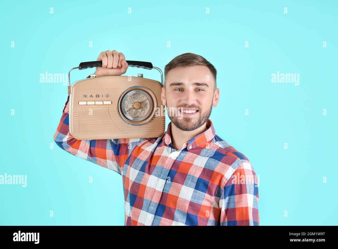 Young man listening to radio against color background Stock Photo - Alamy