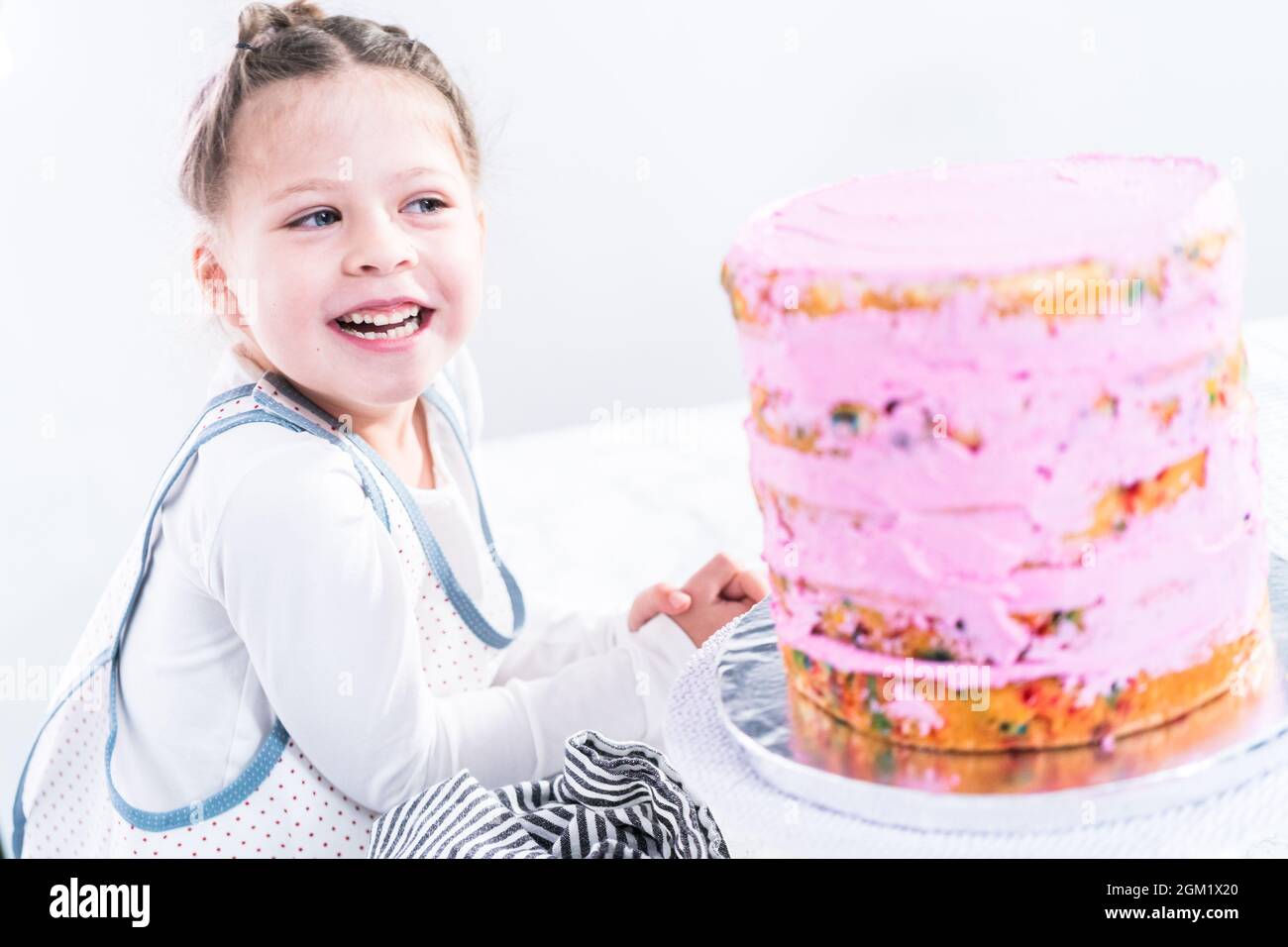 Little girl helping to bake tall funfetti cake with pink buttercream ...