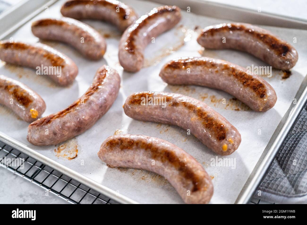 Freshly cooked in oven beer bratwursts on a baking sheet lined with ...