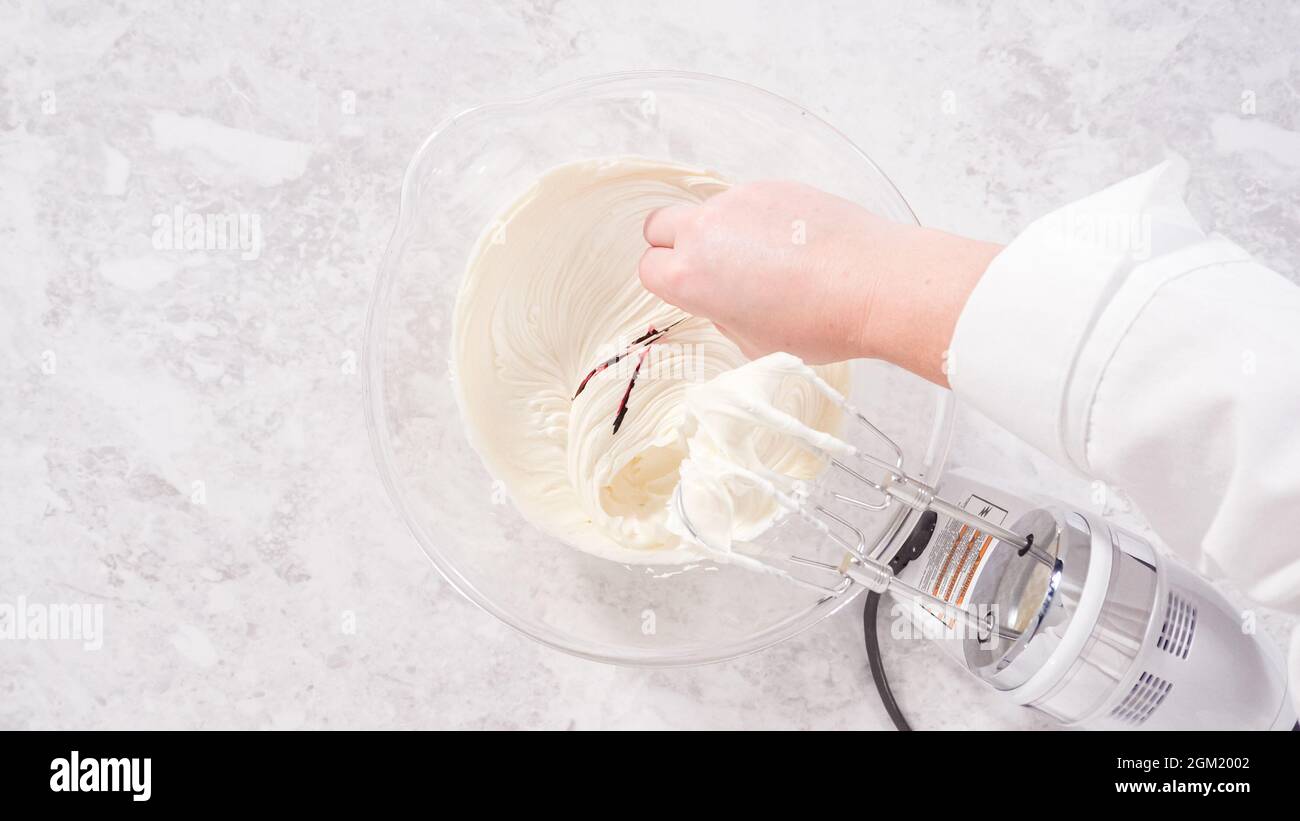 Flat lay. Step by step. Mixing in pink food coloring into a vanilla ...