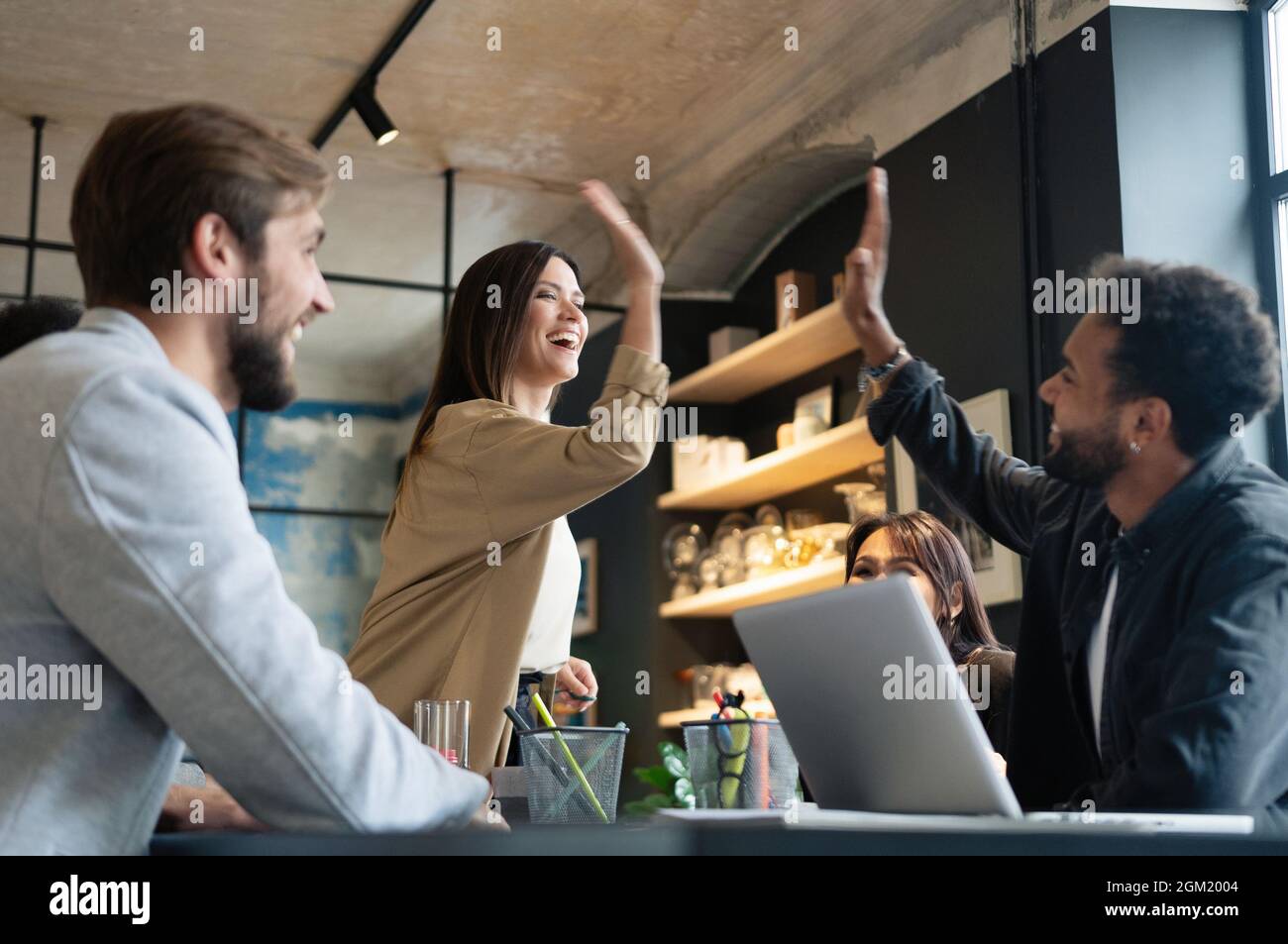 Two cheerful young business people giving high-five while their ...