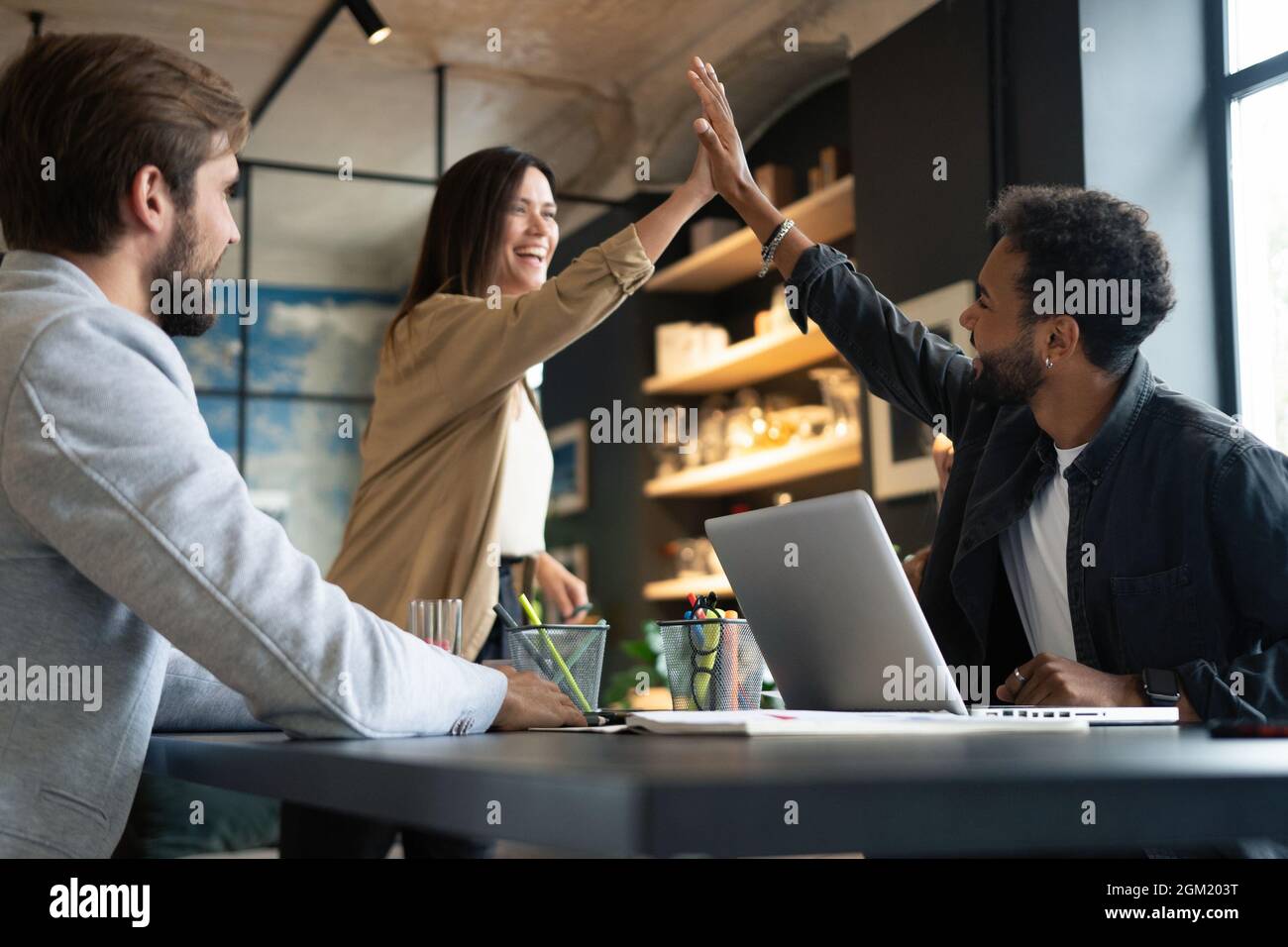 Two cheerful young business people giving high-five while their ...