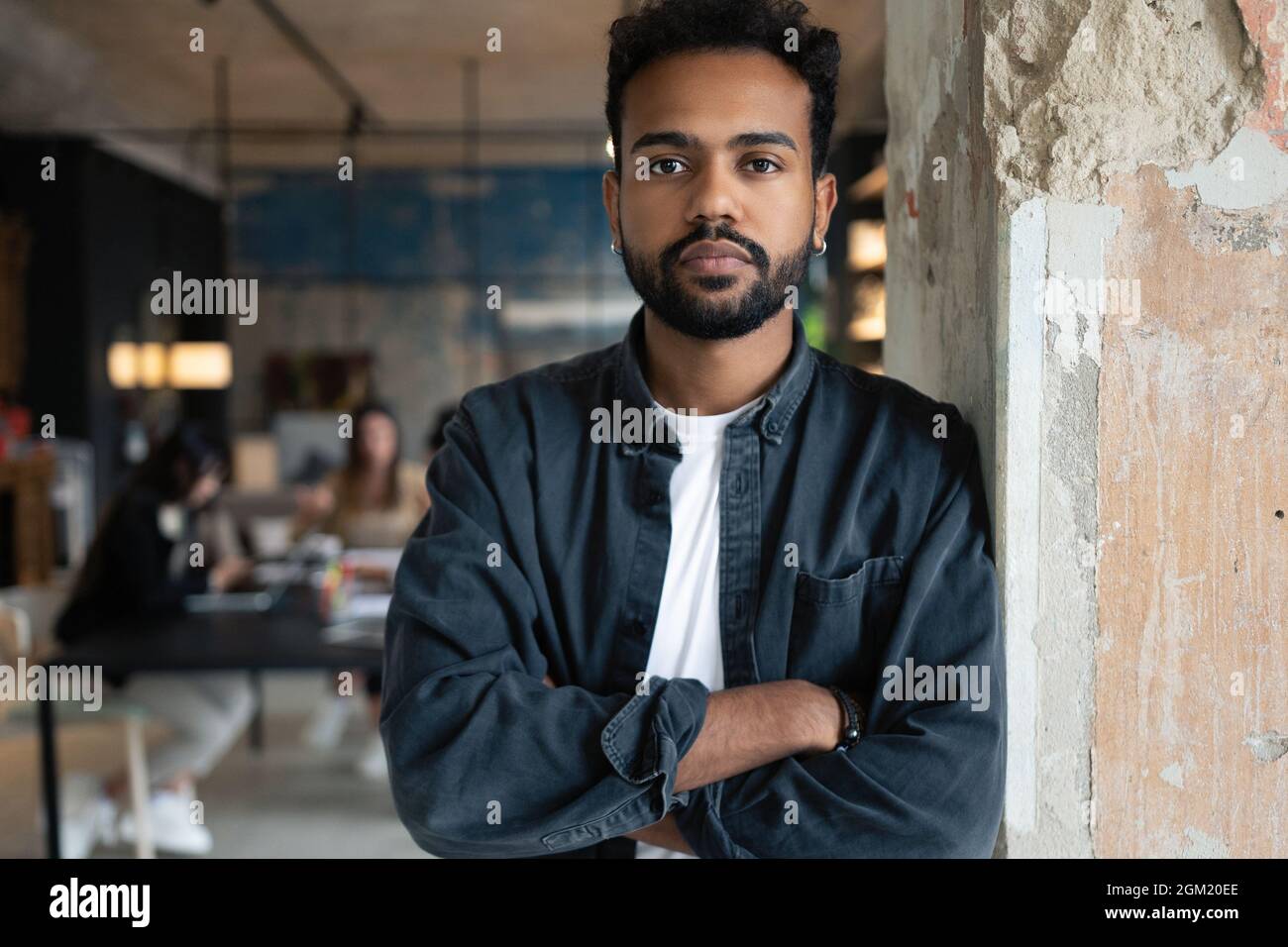 Portrait of mixed-race young man standing in office with colleagues ...