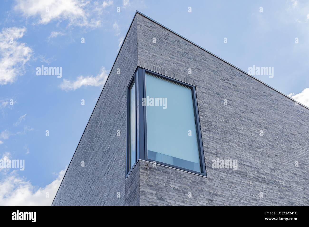 Sharp angle of a modern stone building with a large window in the ...