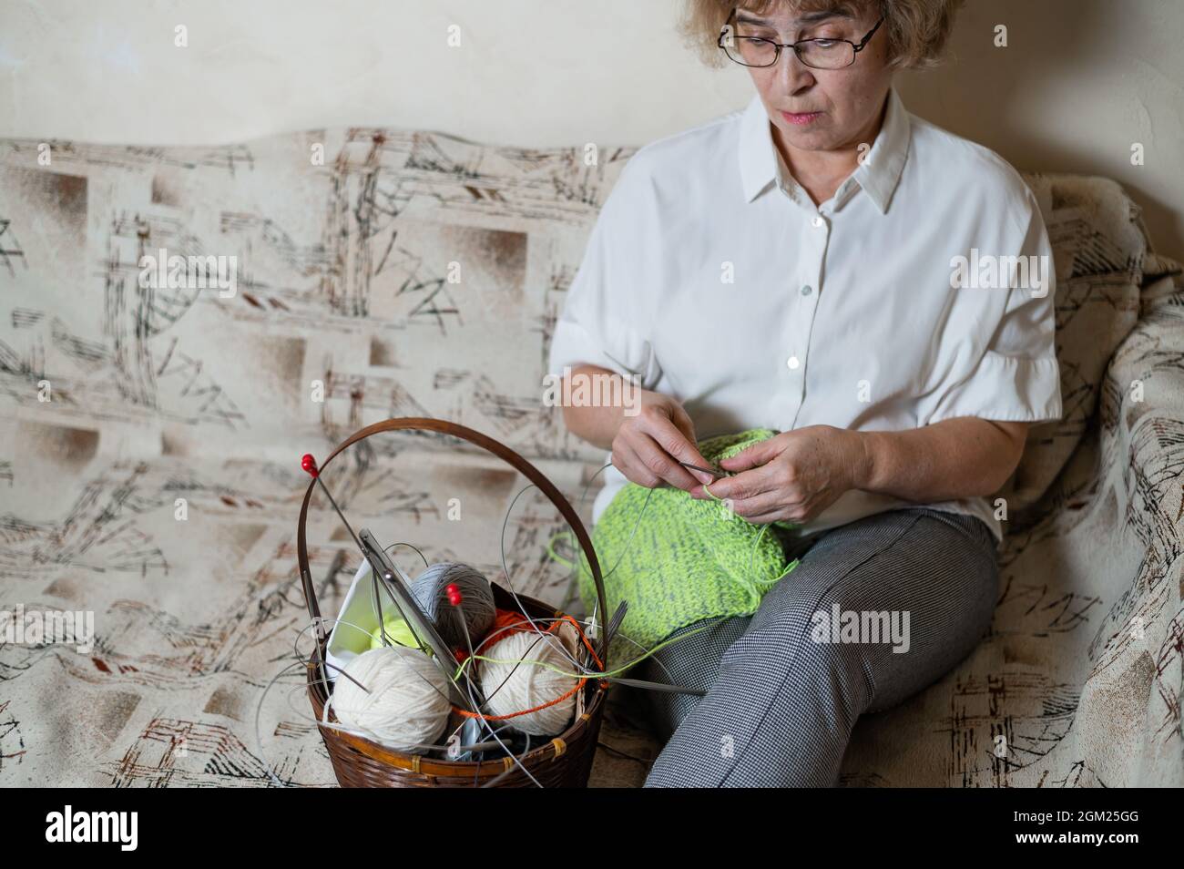An elderly Caucasian woman knits sitting on a couch Stock Photo - Alamy