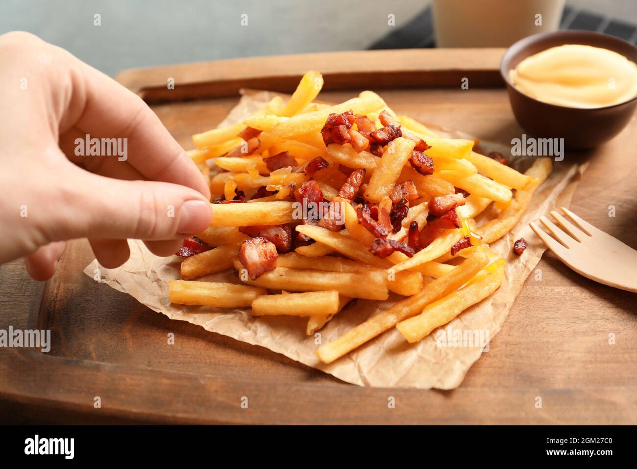 Person eating french fries and bacon at table Stock Photo - Alamy