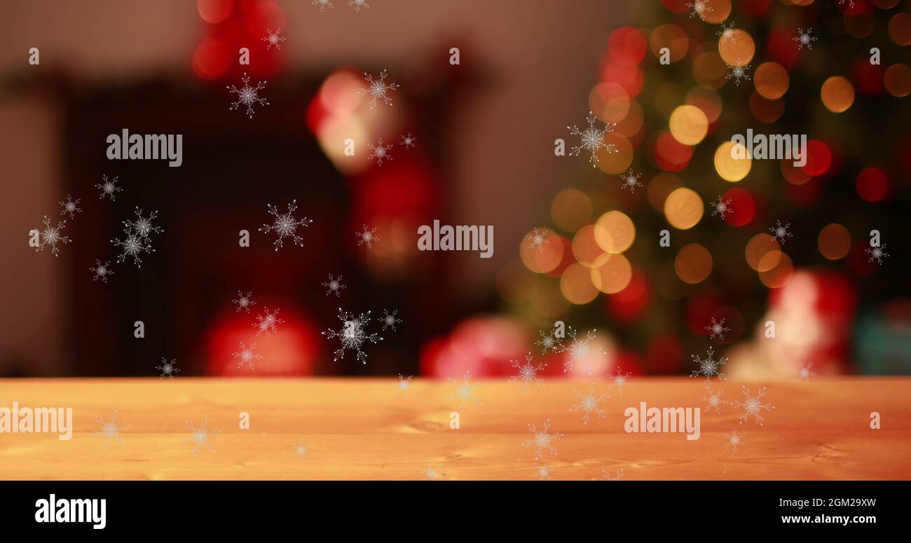 Snowflakes falling against flickering fairy lights on Christmas tree ...