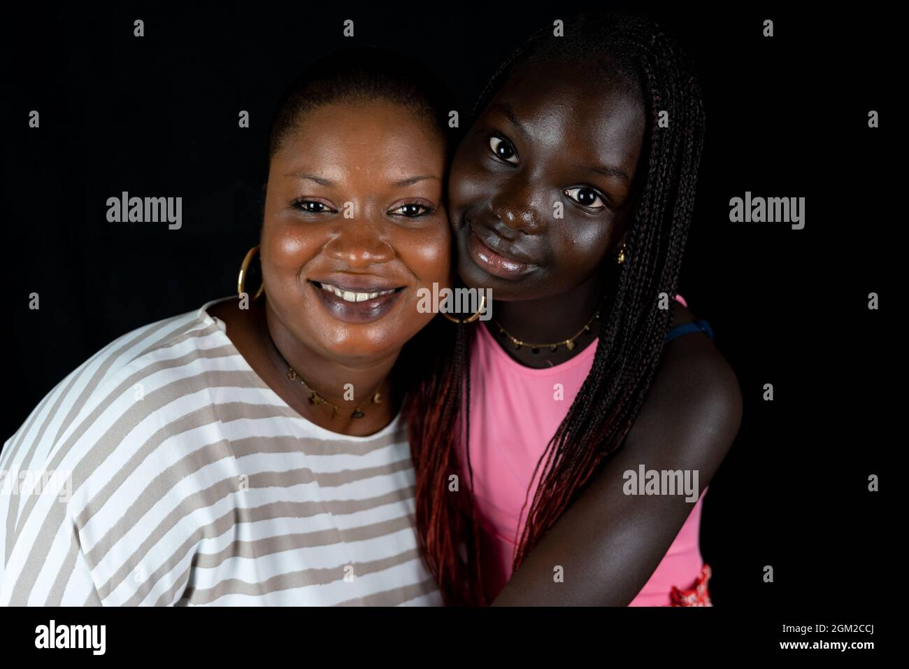 African american mother and daughter smiling happy hugging on black ...